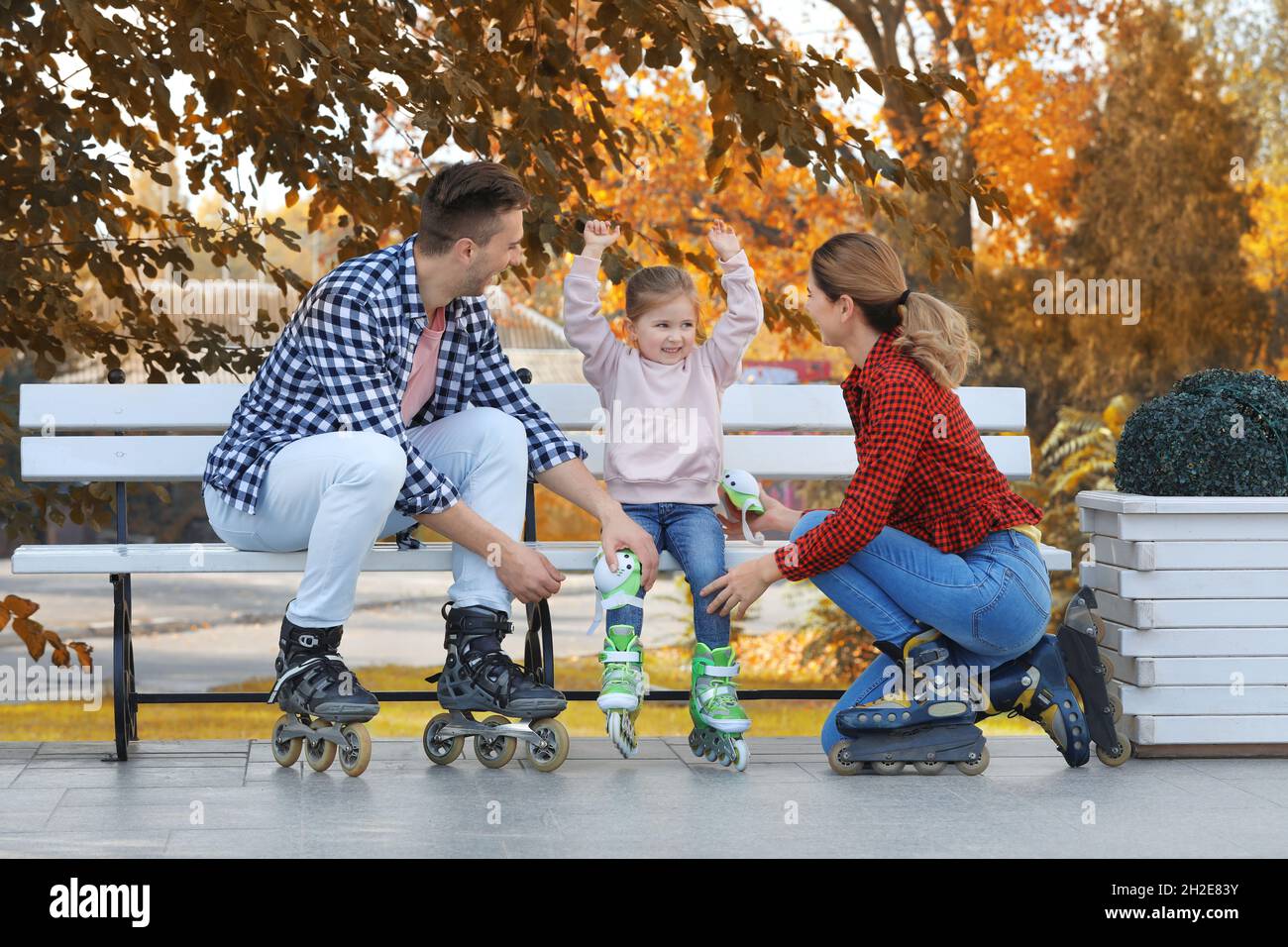 Happy family wearing roller skates on bench outdoors Stock Photo - Alamy