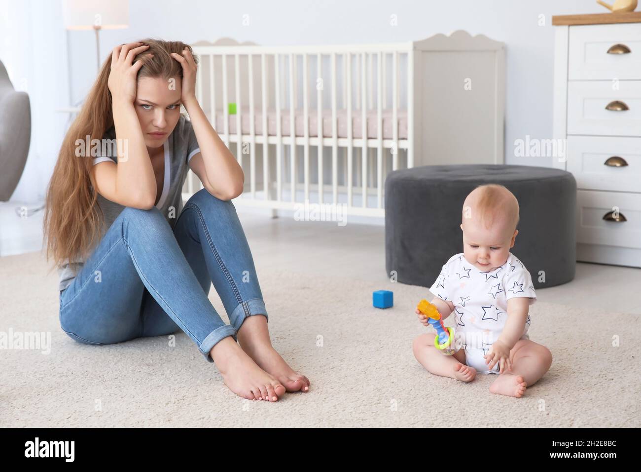 Young mother suffering from postnatal depression and cute baby girl at ...