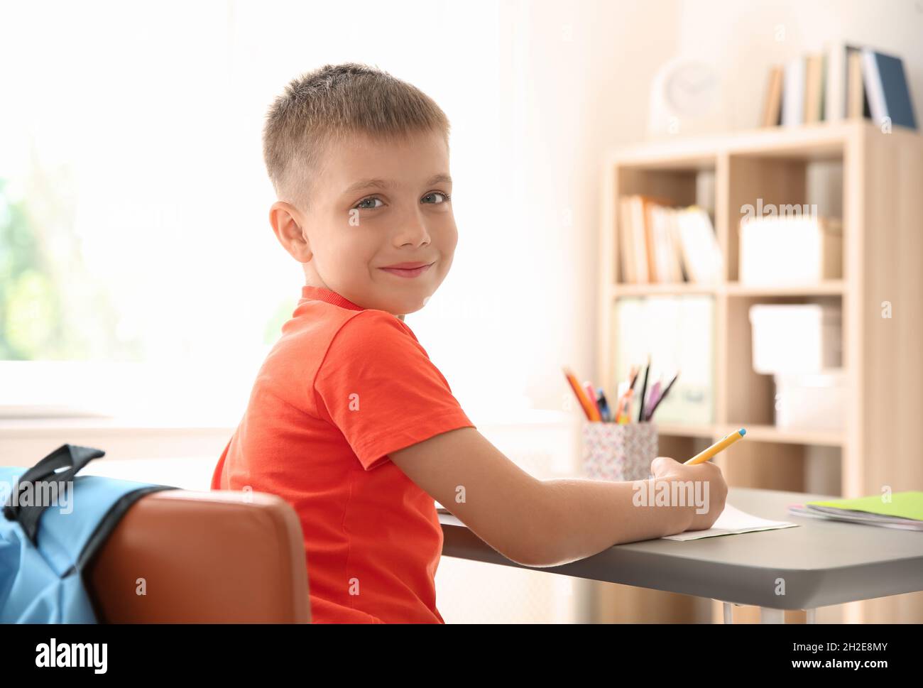 Cute little child doing assignment at desk in classroom. Elementary ...