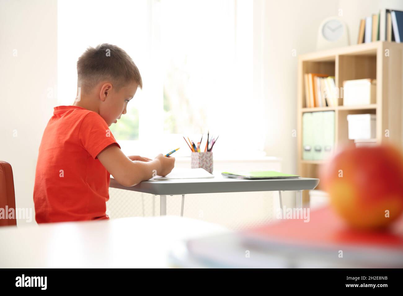 Cute little child doing assignment at desk in classroom. Elementary ...