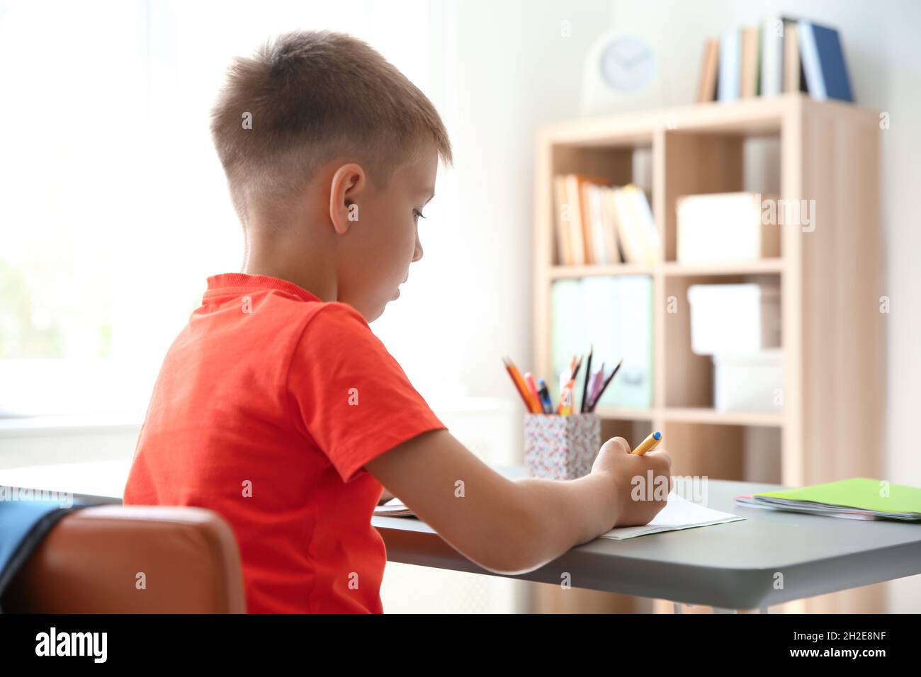Cute little child doing assignment at desk in classroom. Elementary ...