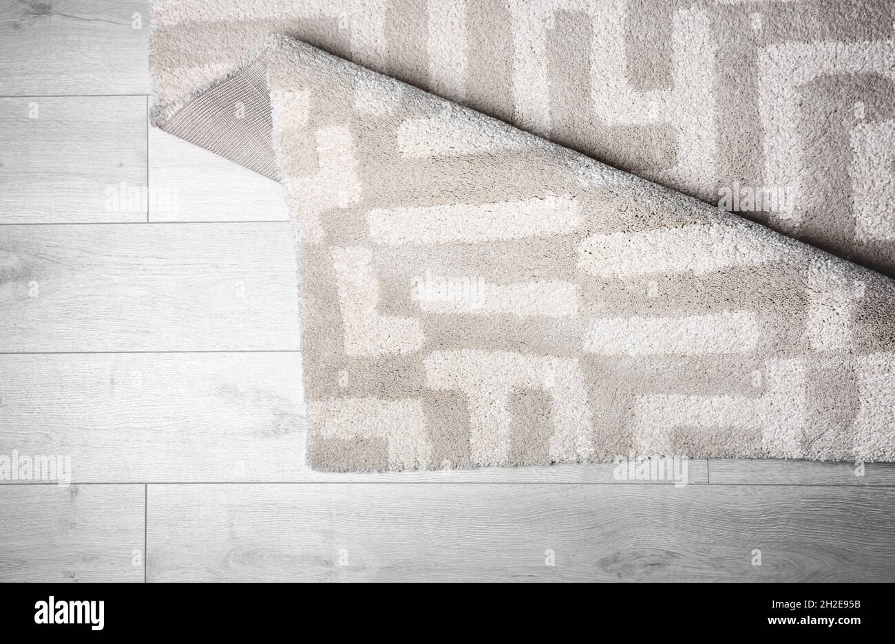 Light carpet with pattern on wooden floor Stock Photo - Alamy