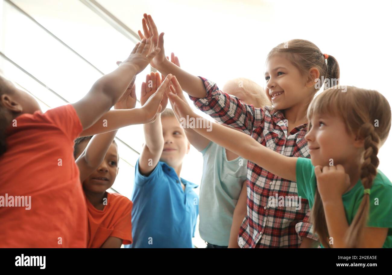 Little children putting their hands together on light background. Unity ...