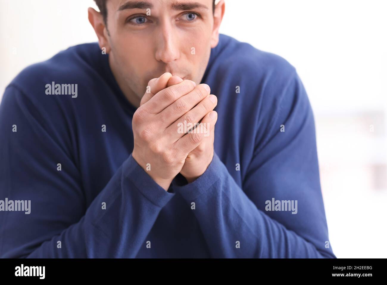 Sad young man suffering from cold on blurred background Stock Photo - Alamy