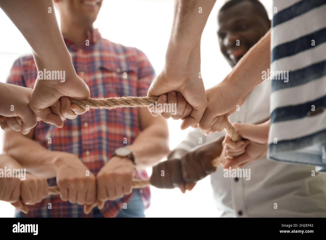People holding rope together on light background, closeup of hands ...