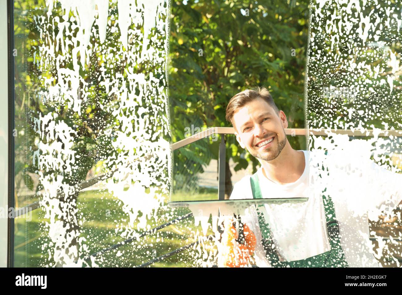 Male janitor cleaning window, view from inside Stock Photo - Alamy