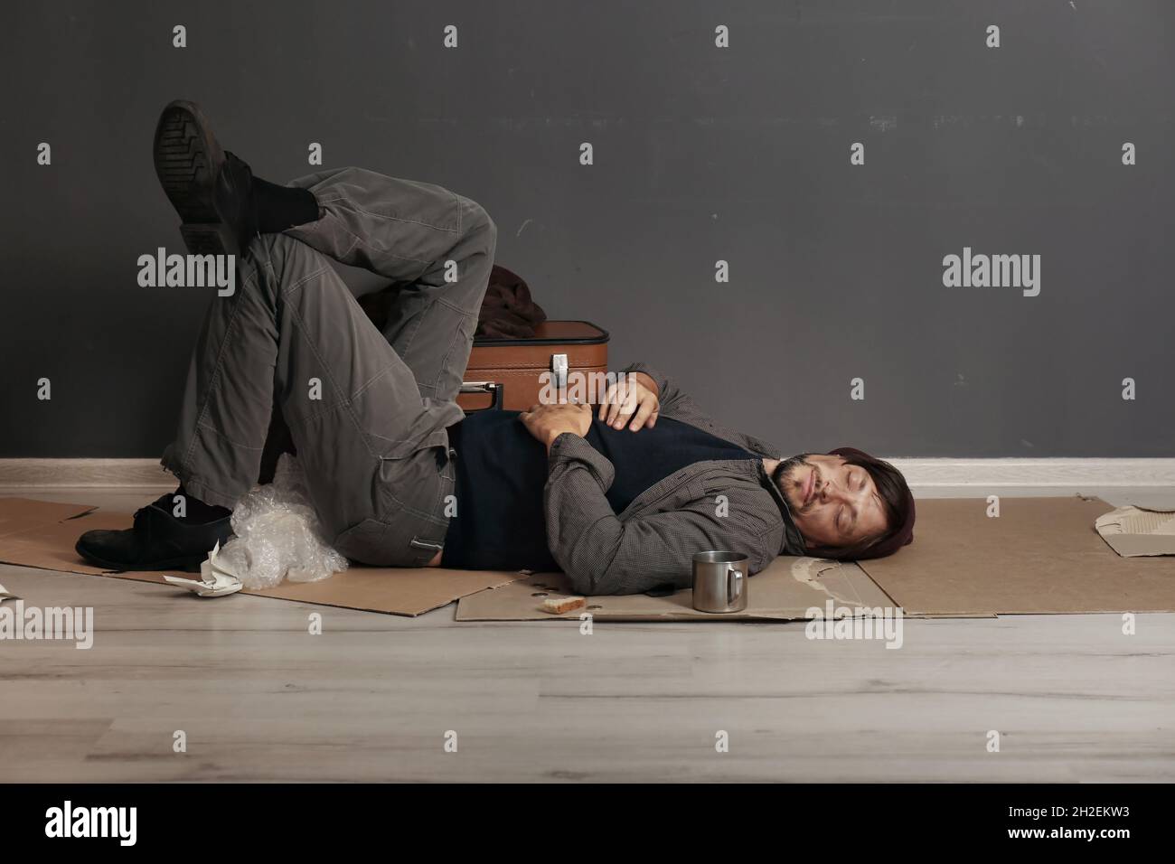 Poor homeless man sleeping on floor near dark wall Stock Photo - Alamy