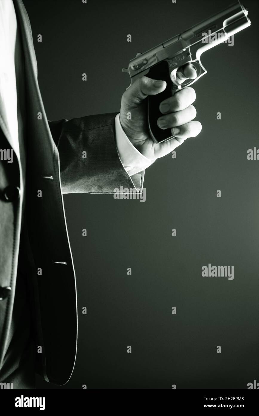 Retro secret agent with pistol revolver gun in hand in vintage crime ...