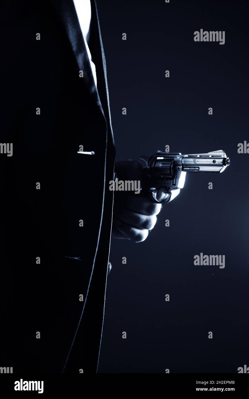 Retro secret agent with pistol revolver gun in hand in vintage crime ...