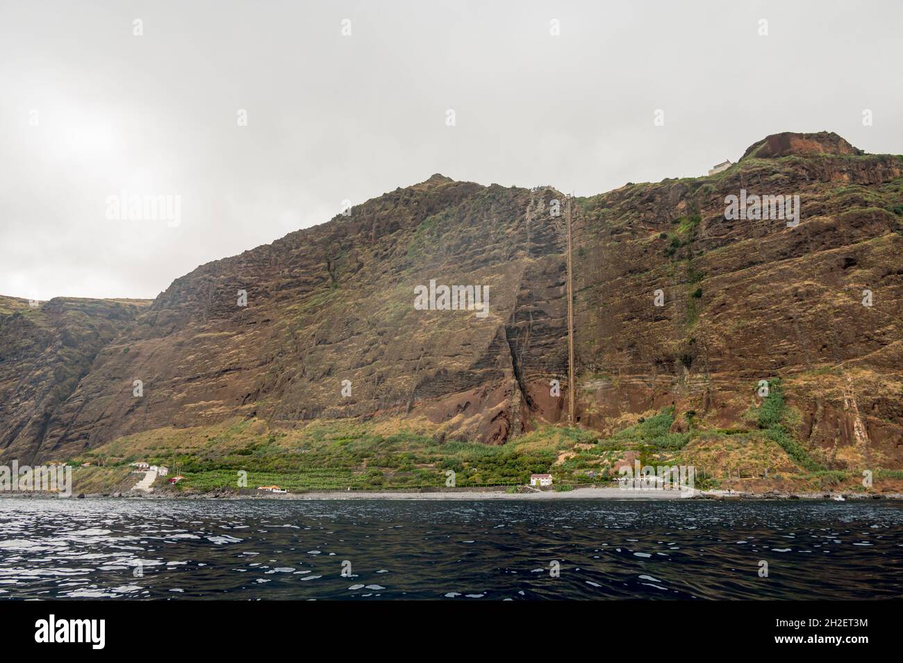 Panoramic view of sheer volcanic cliff rising above ocean Stock Photo ...