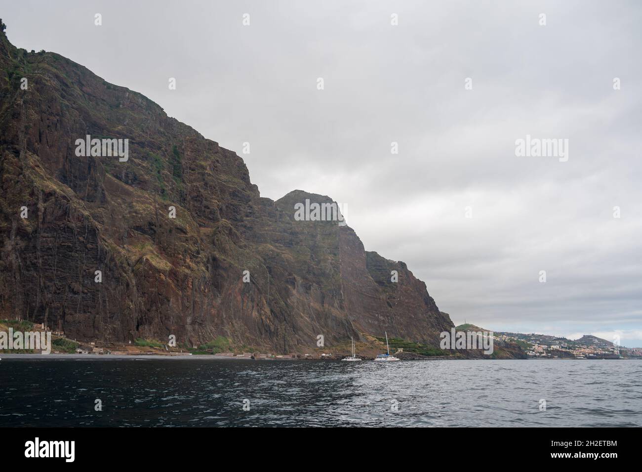 Panoramic view of sheer volcanic cliff rising above ocean Stock Photo ...