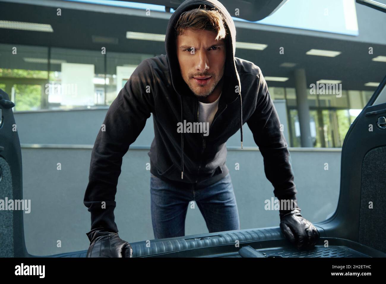 Angry european robber looking in car trunk. View from auto trunk with ...