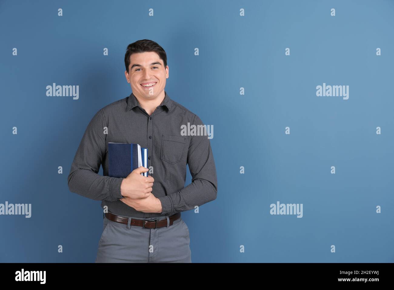 Portrait of male teacher with notebooks on color background Stock Photo ...