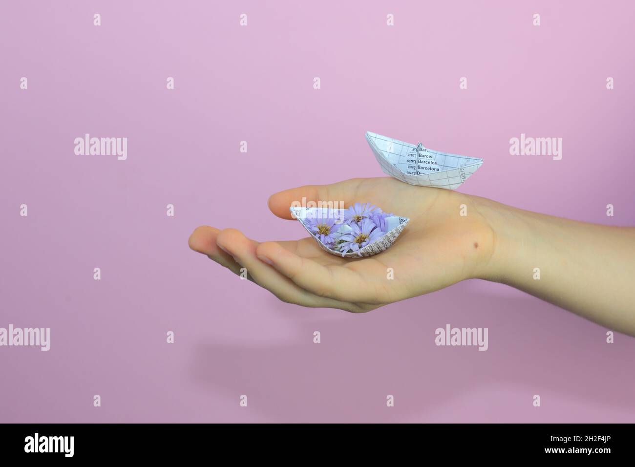 Person's hand holding an origami boat against a pink background Stock ...