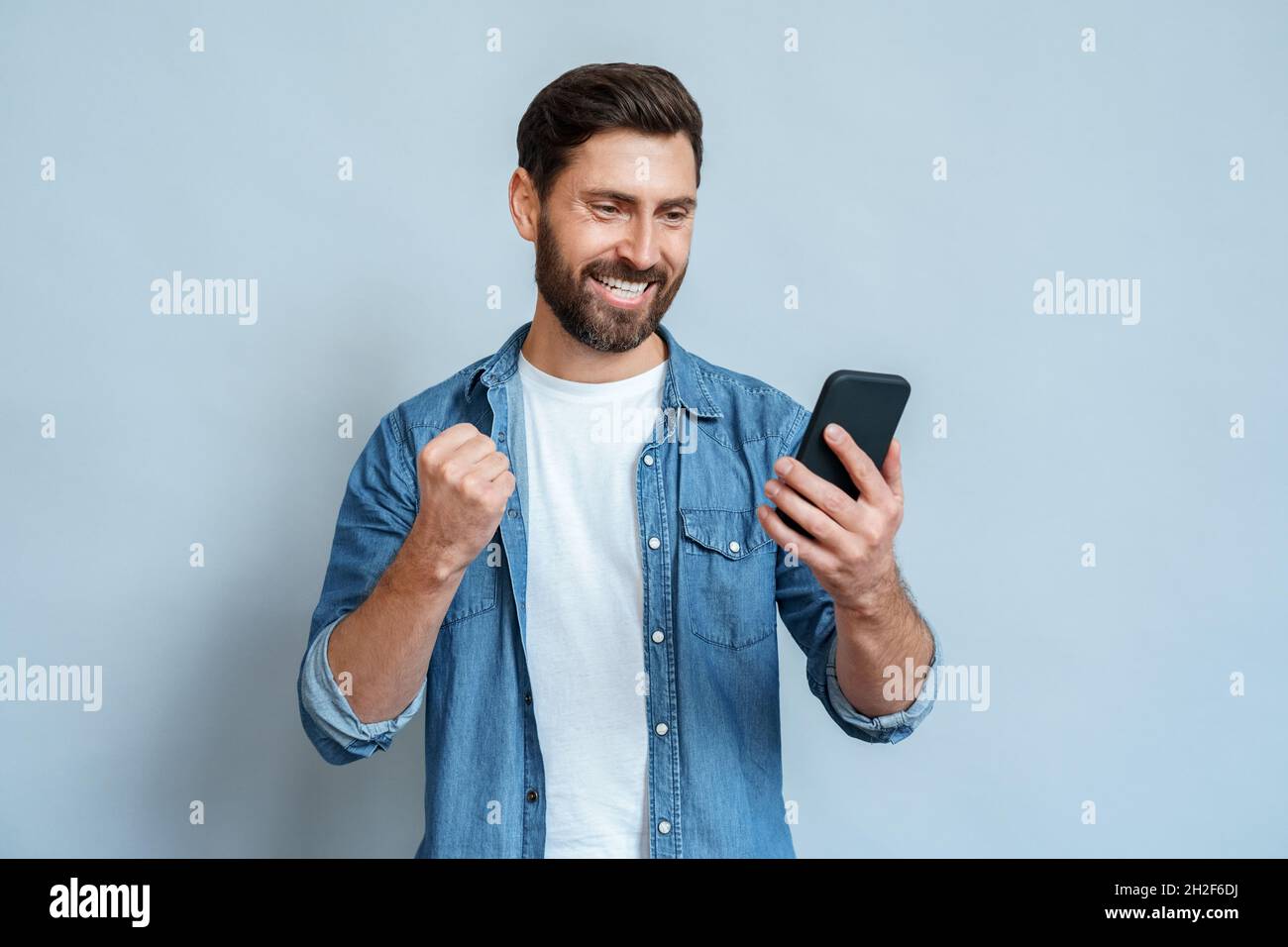 Man Looking At Mobile Phone Screen Gesturing Yes With Clenched Fist