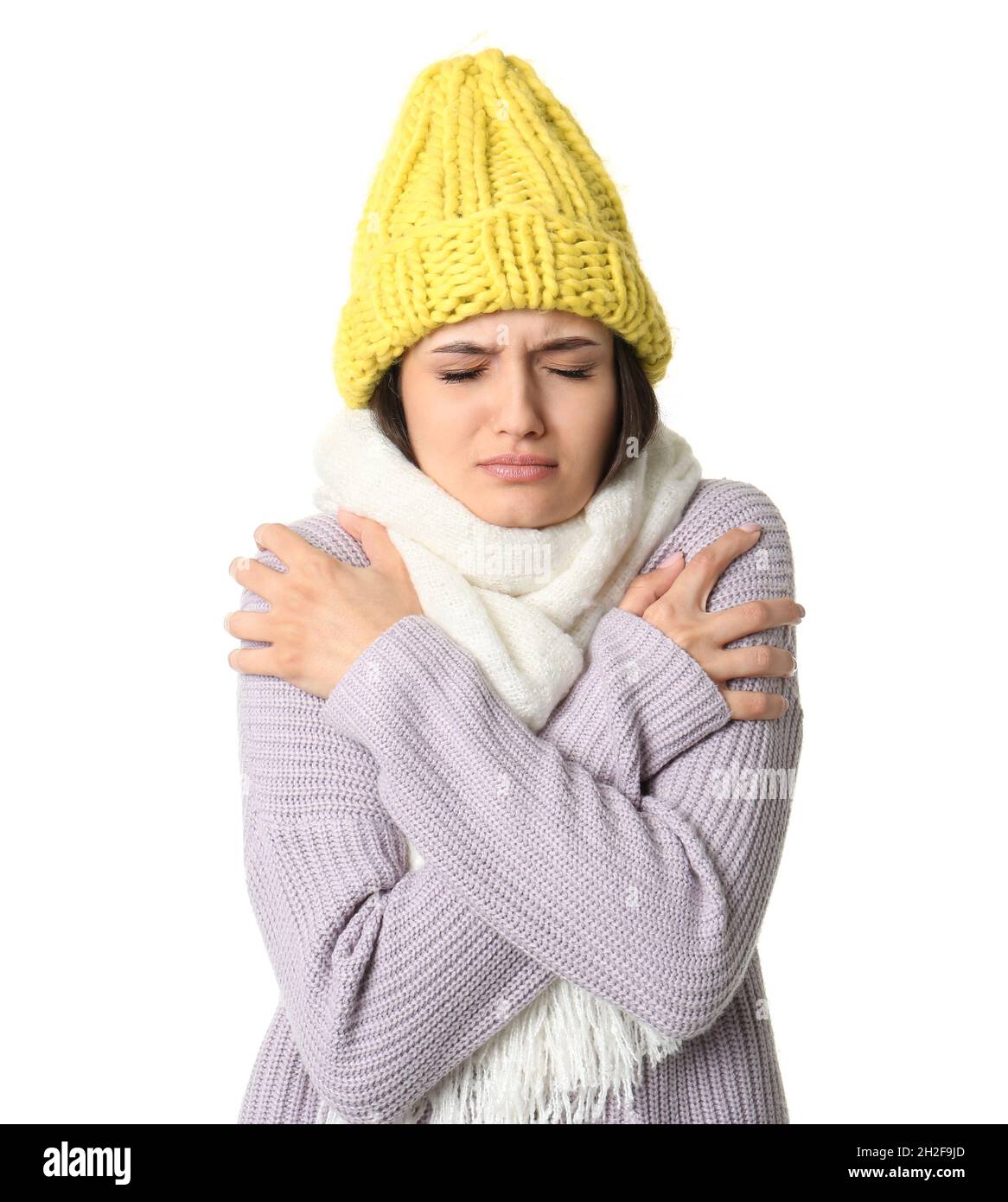 Young woman in warm clothes suffering from cold on white background ...