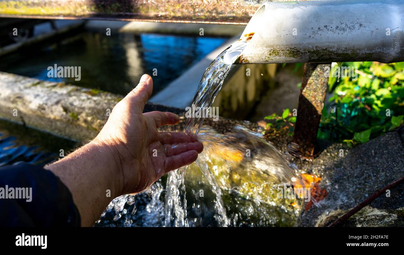 hand that cuts the stream of water that flows from a pipe in a fountain ...
