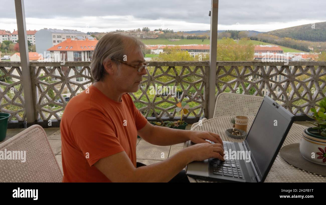 middle-aged man working with his computer on a terrace where you can ...