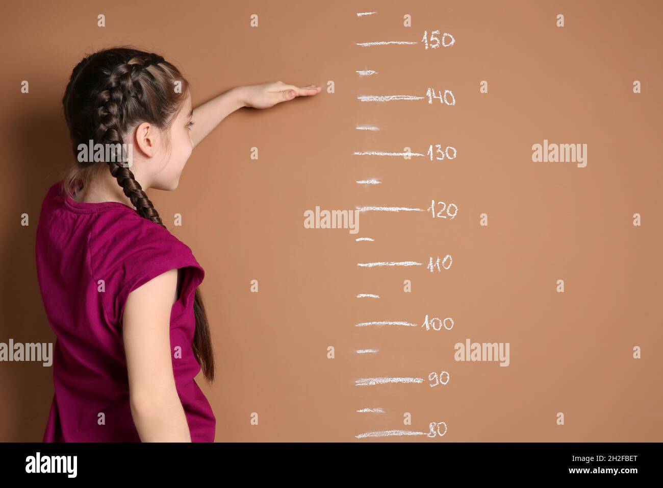 Little girl measuring her height on color background Stock Photo - Alamy