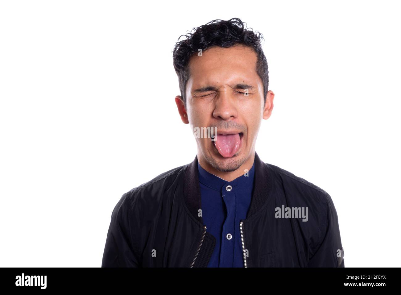 Young adult young man sticking out his tongue and closing his eyes ...