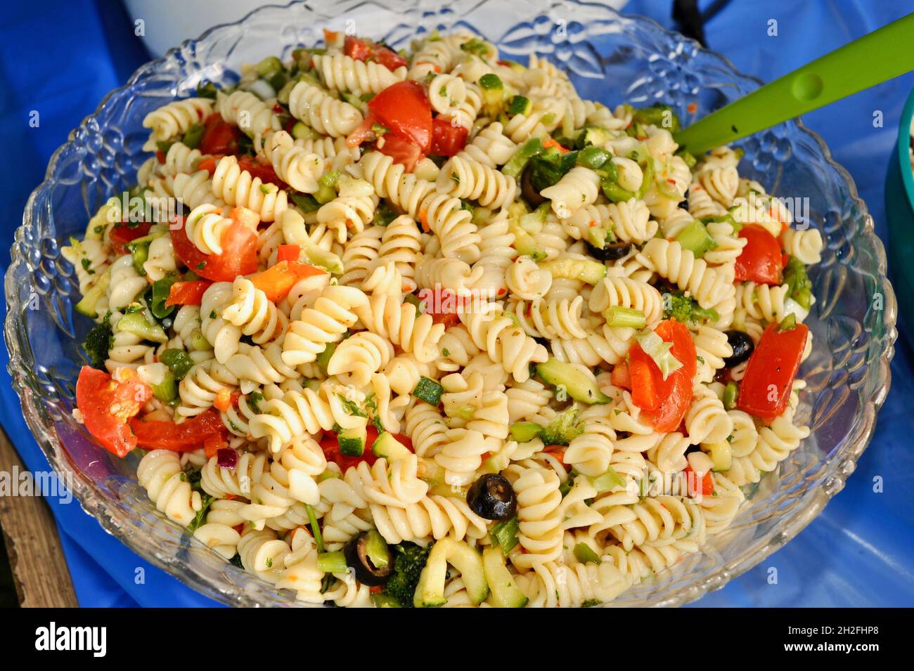 Large glass bowl of fresh, homemade fusilli pasta salad on picnic table ...