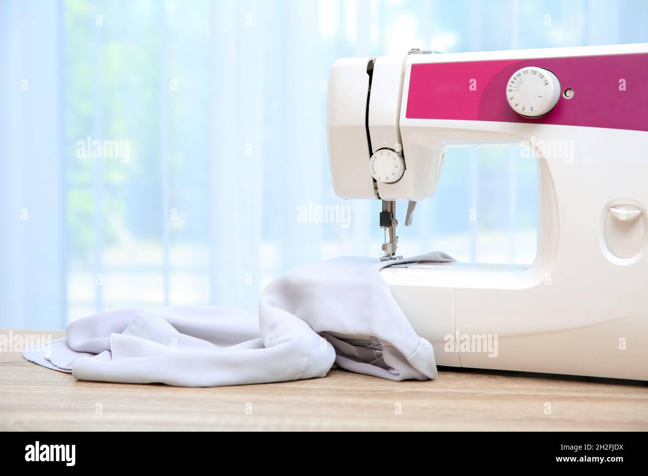 Sewing machine on table near window indoors Stock Photo - Alamy