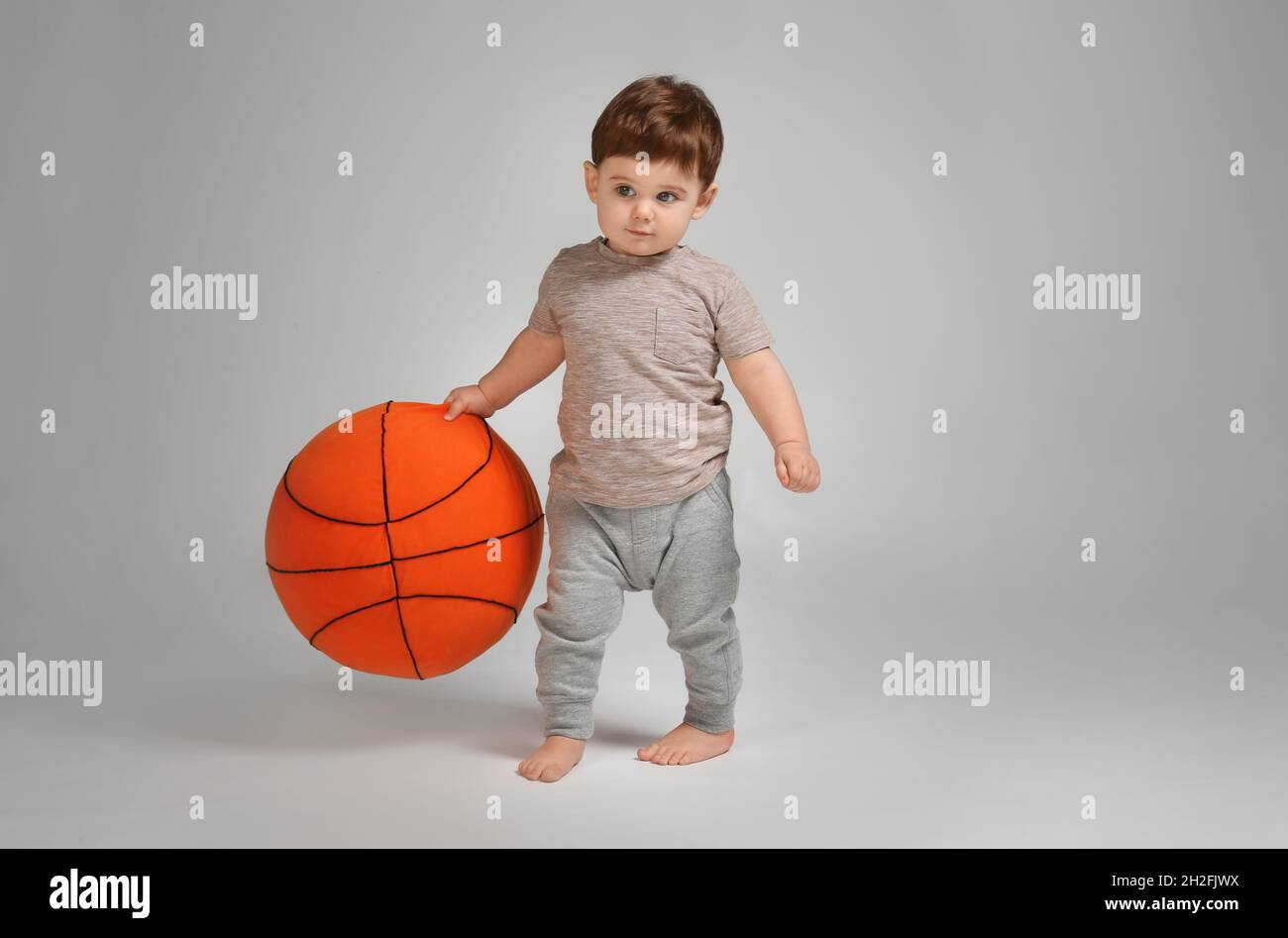 Cute baby learning to walk and playing on grey background Stock Photo ...
