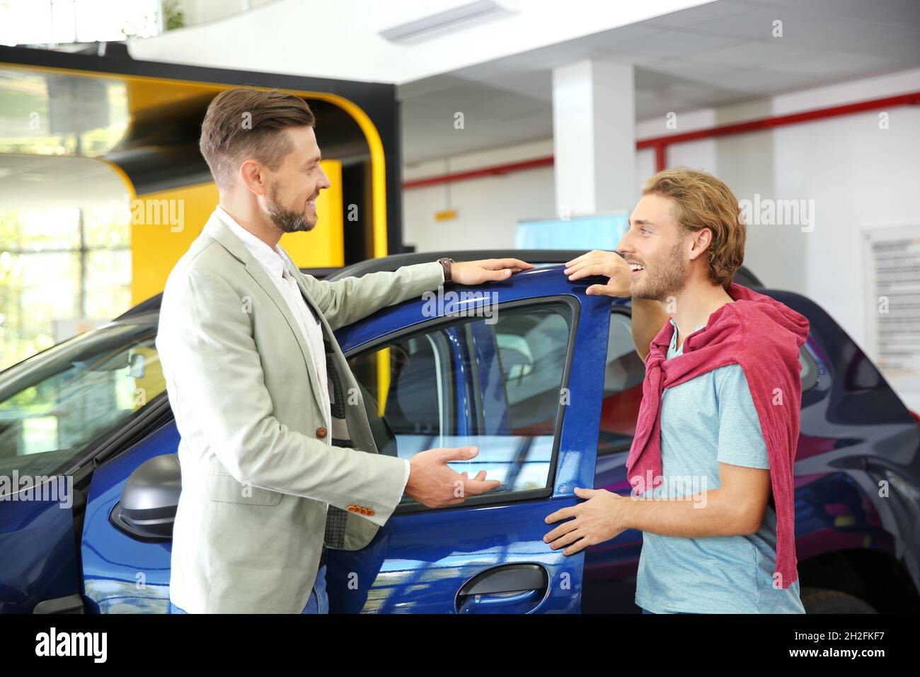 Salesman with customer in modern car dealership Stock Photo - Alamy