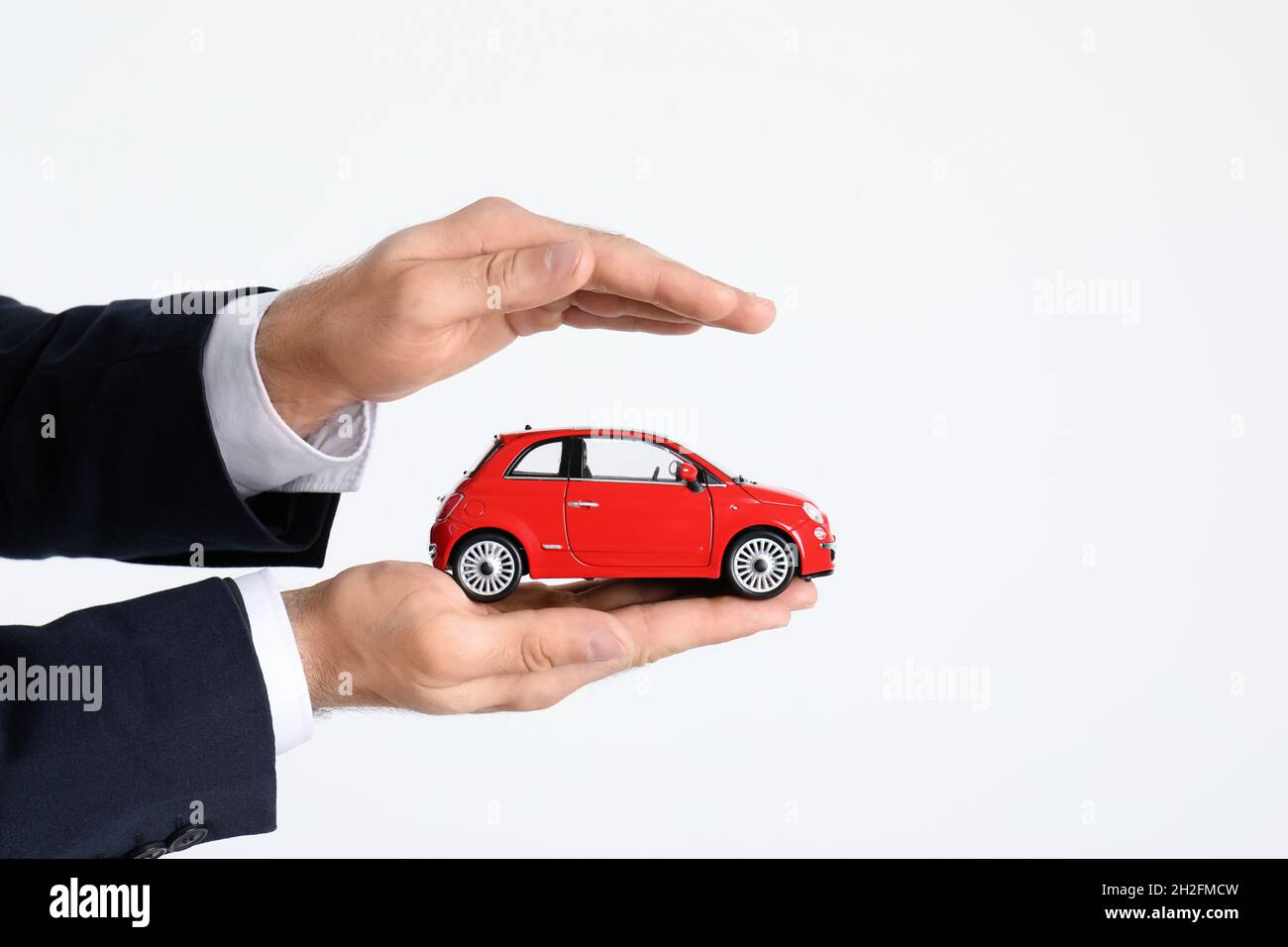 Male insurance agent holding toy car on white background, closeup ...