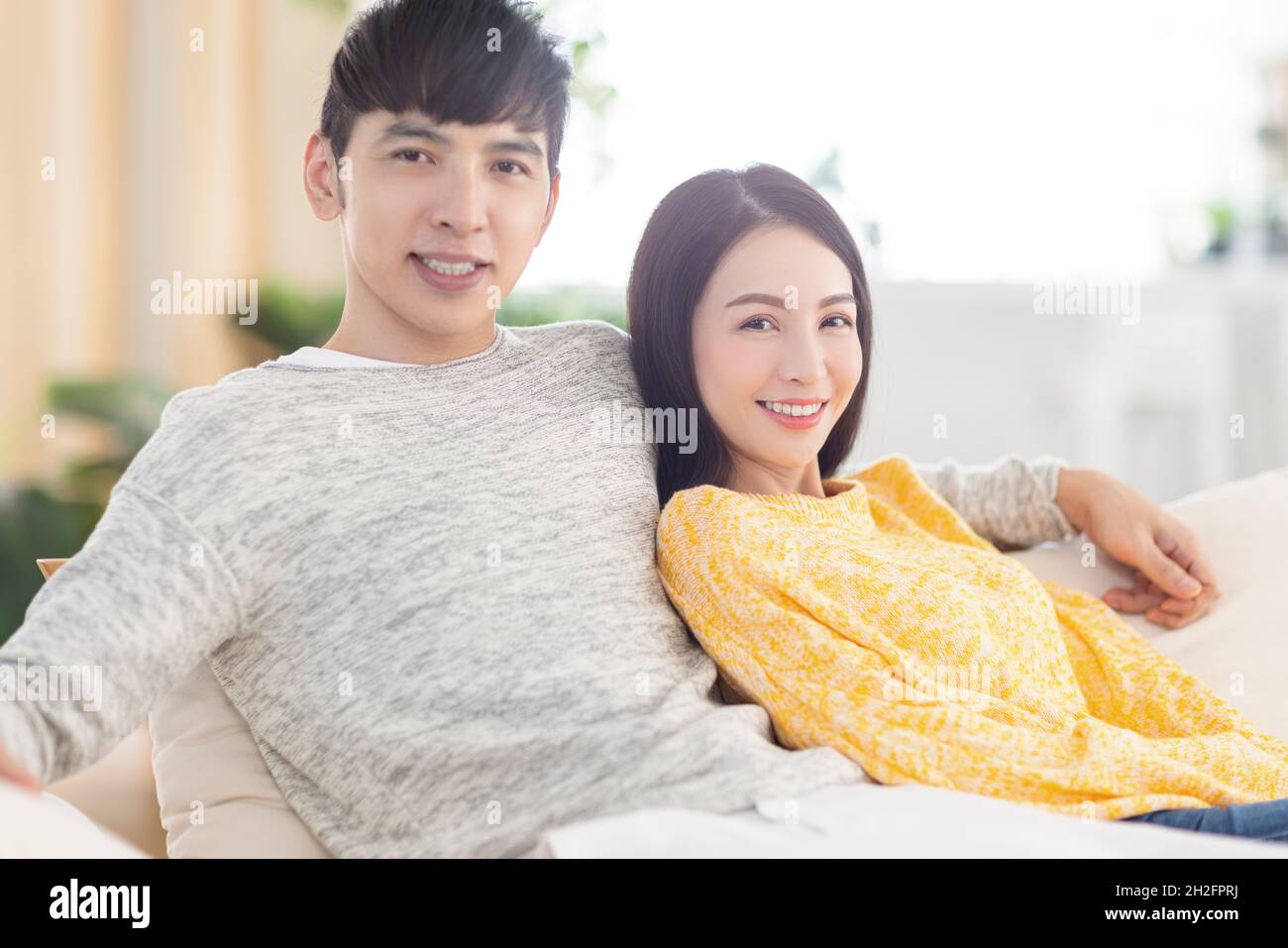 Young happy couple sitting together in the living room Stock Photo - Alamy