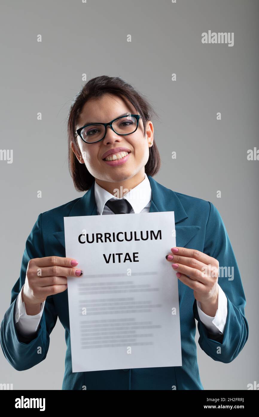Smart young businesswoman in a stylish suit holding up a CV in front of ...