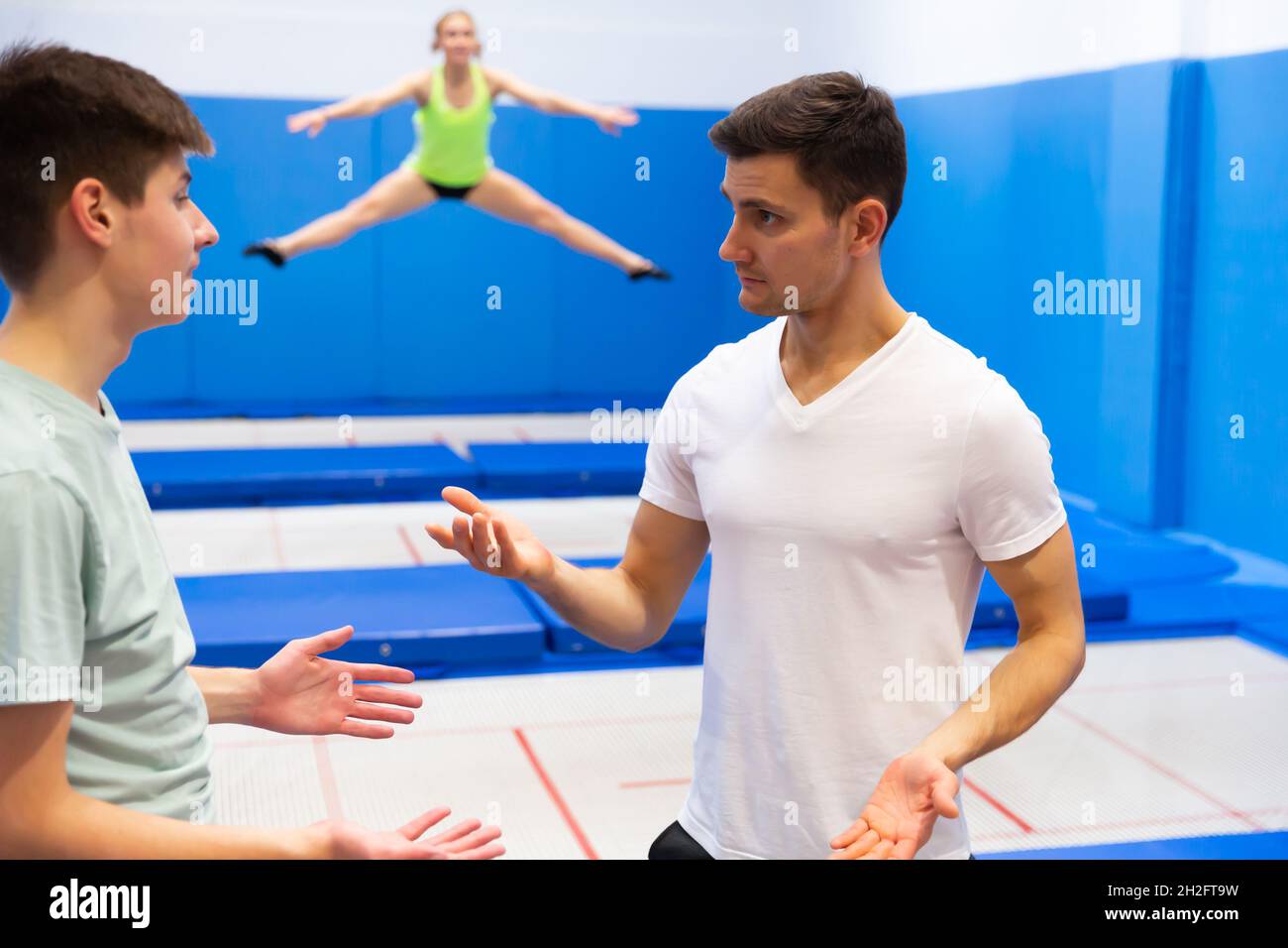Coach holding training with teenager in trampoline room Stock Photo - Alamy