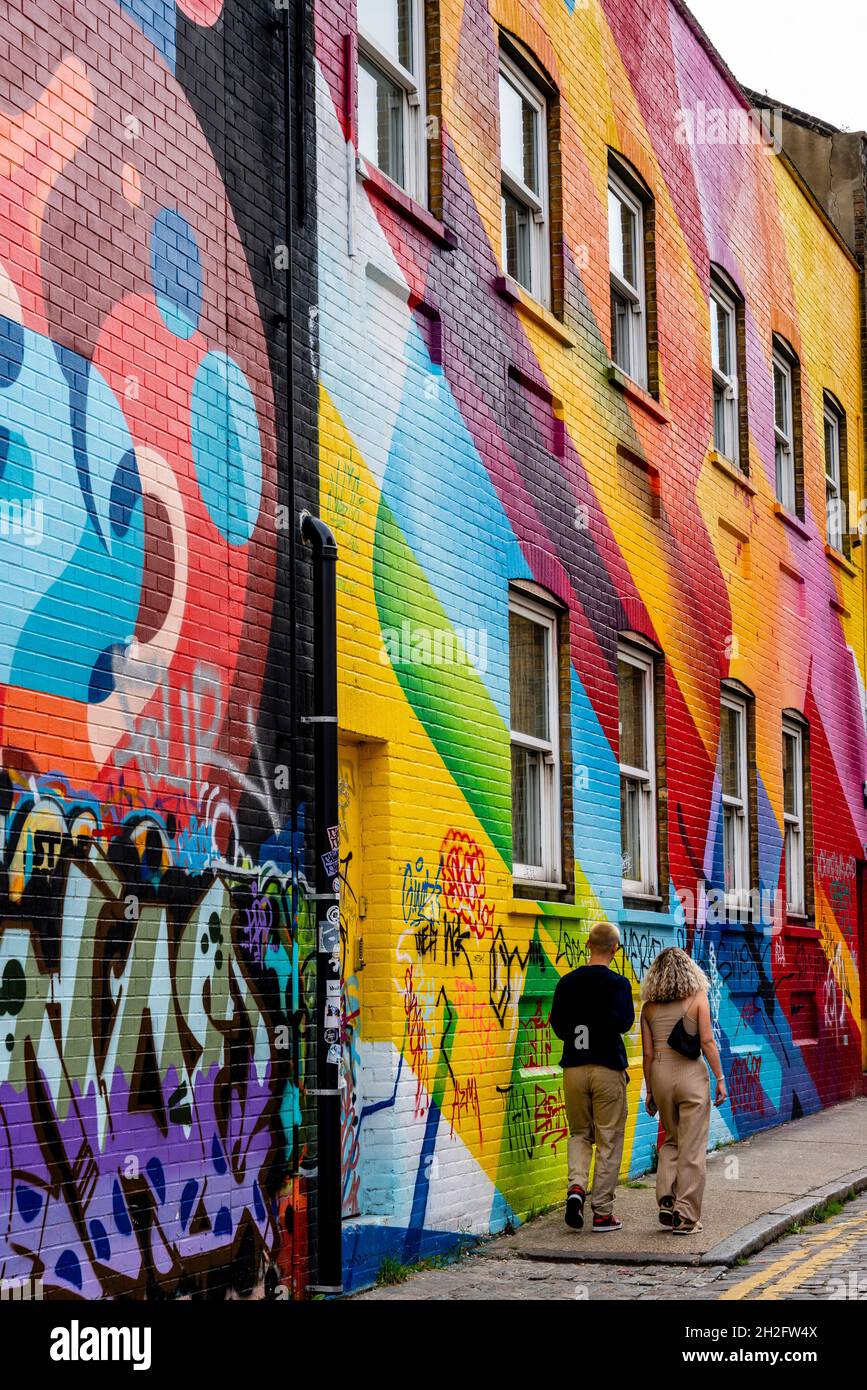 People Walk Past Buildings Covered In Colourful Graffiti, Shoreditch ...