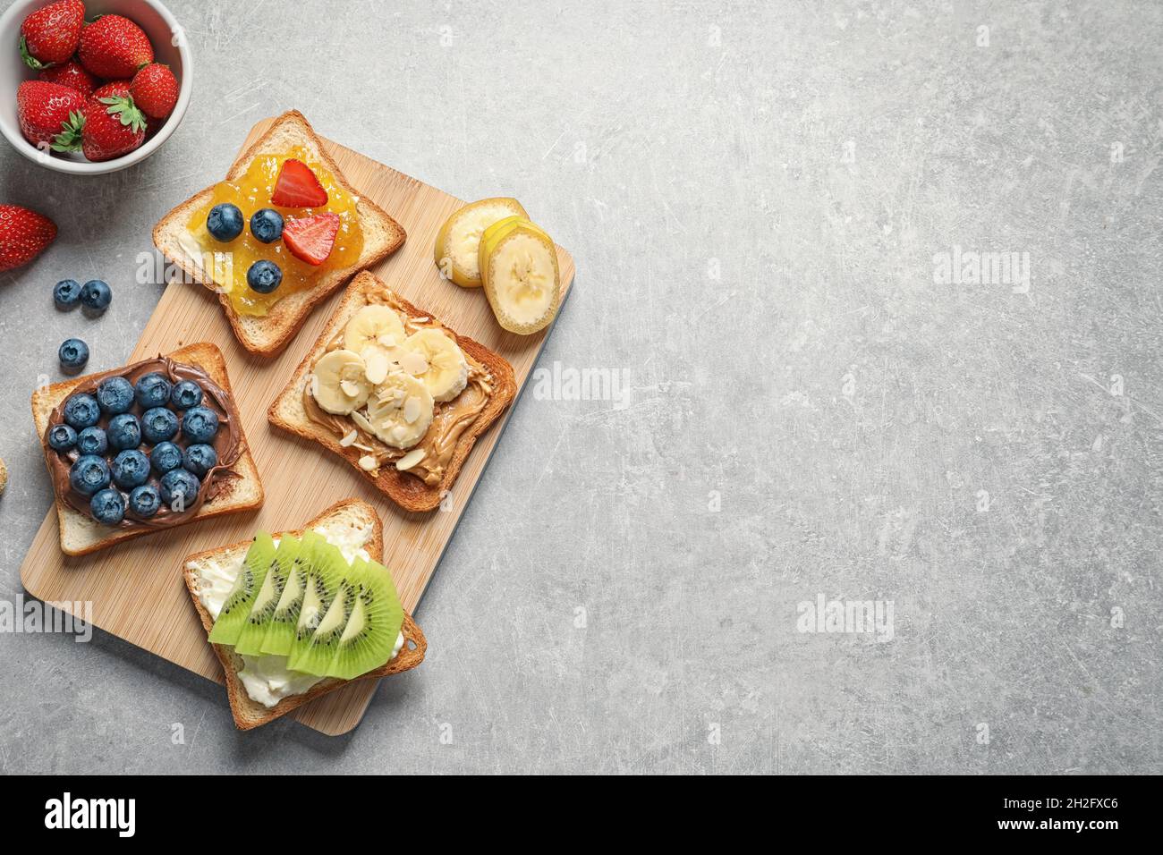 Flat lay composition with toast bread and different toppings on grey ...