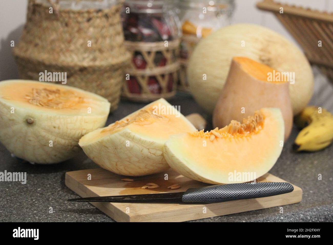 Kitchen table with cut and whole melons Stock Photo - Alamy