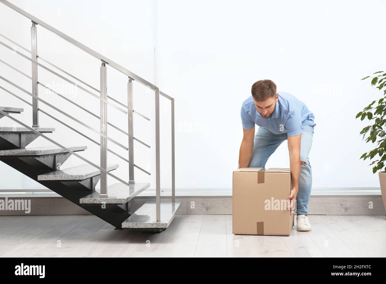 Young man lifting carton box indoors. Posture concept Stock Photo - Alamy