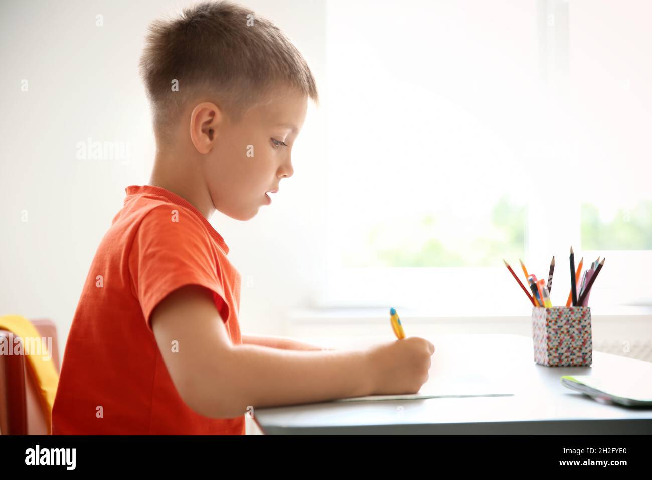 Cute little child doing assignment at desk in classroom. Elementary ...