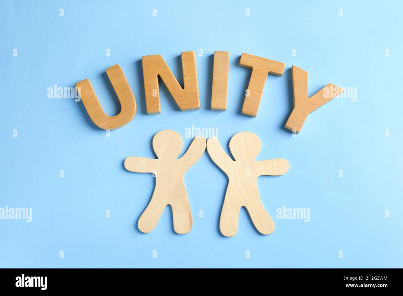 Wooden people giving high five and word UNITY on color background ...