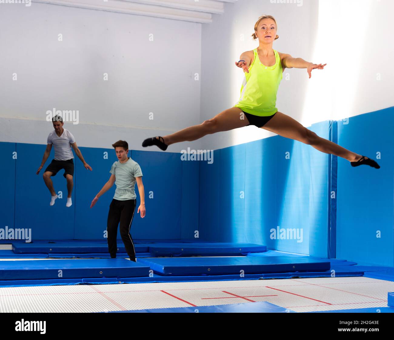 Female gymnast practicing middle split on trampoline Stock Photo - Alamy
