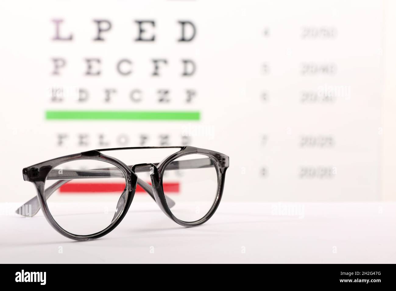 Glasses with corrective lenses on table against eye chart Stock Photo ...