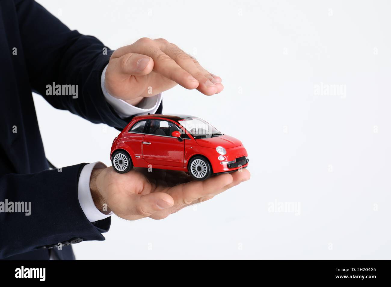 Male insurance agent holding toy car on white background, closeup ...