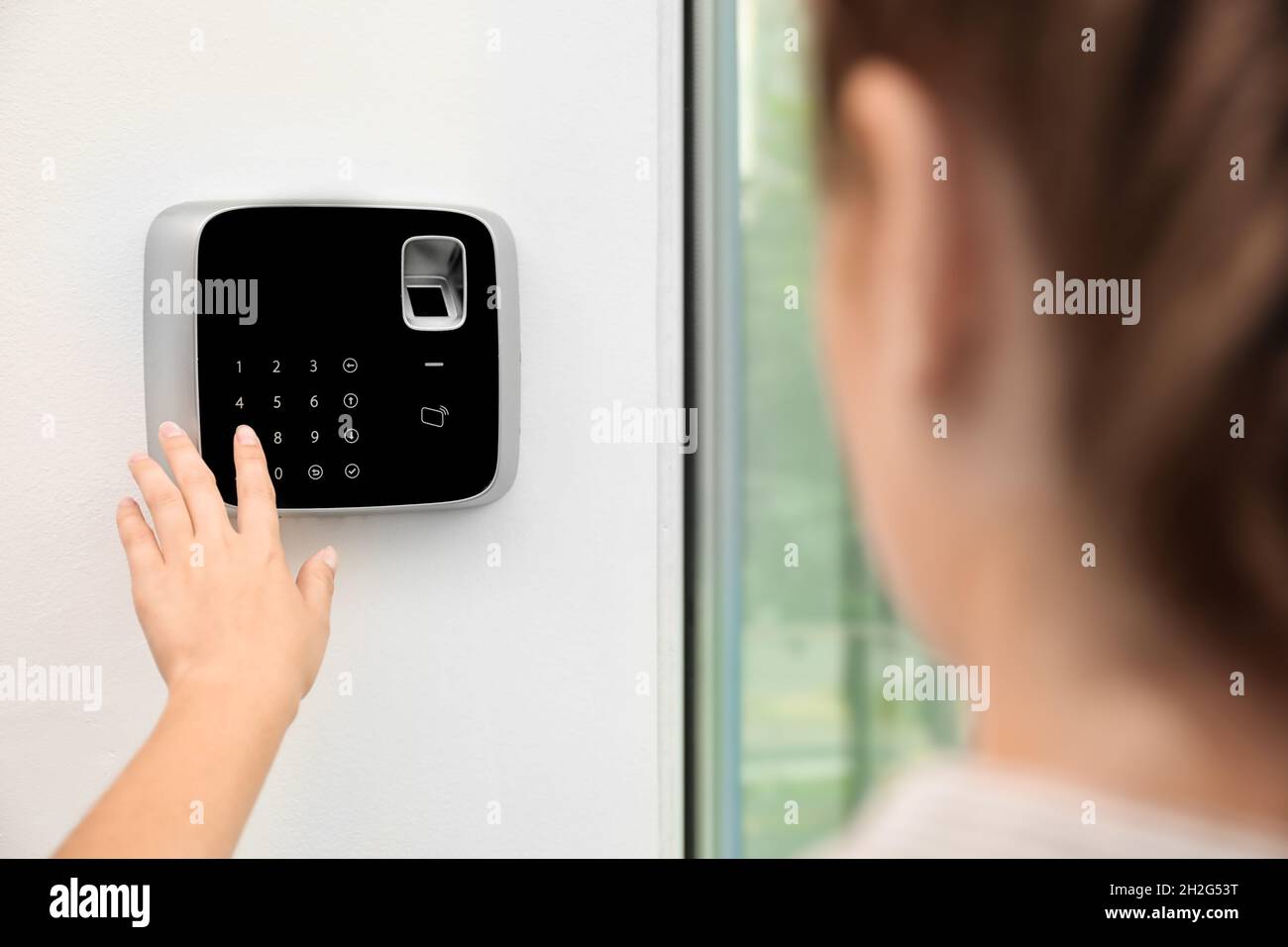 Young woman entering code on alarm system keypad indoors Stock Photo ...
