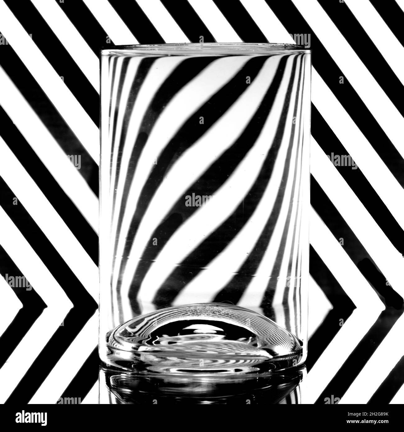 refraction of light by a glass on a black and white striped background ...