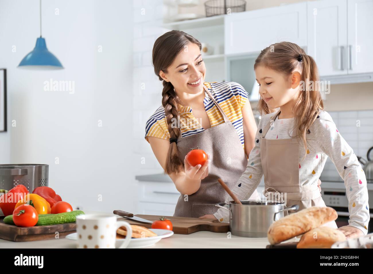 Young nanny with cute little girl cooking together in kitchen Stock ...