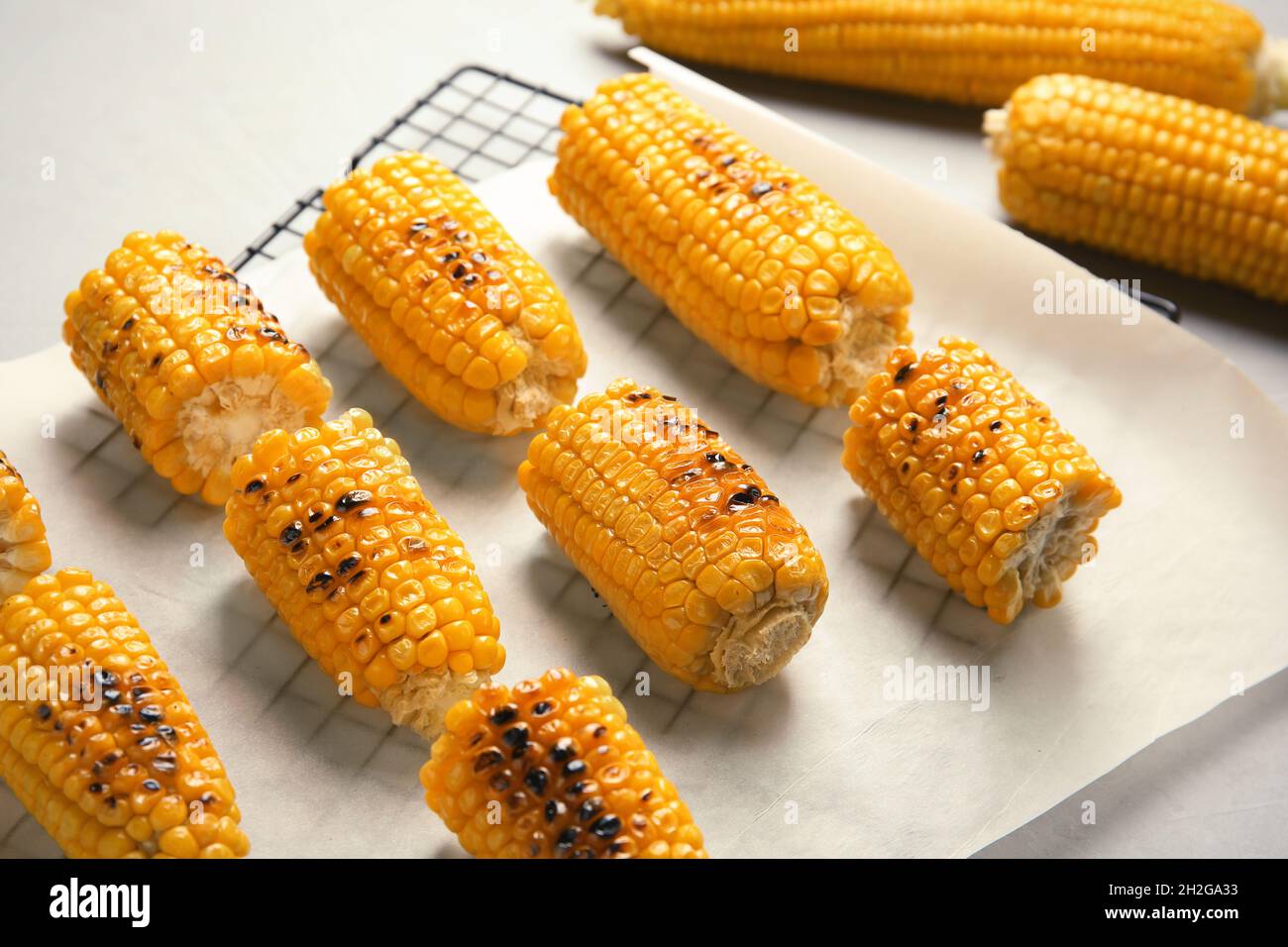 Cooling rack with grilled corn cobs on light background Stock Photo - Alamy