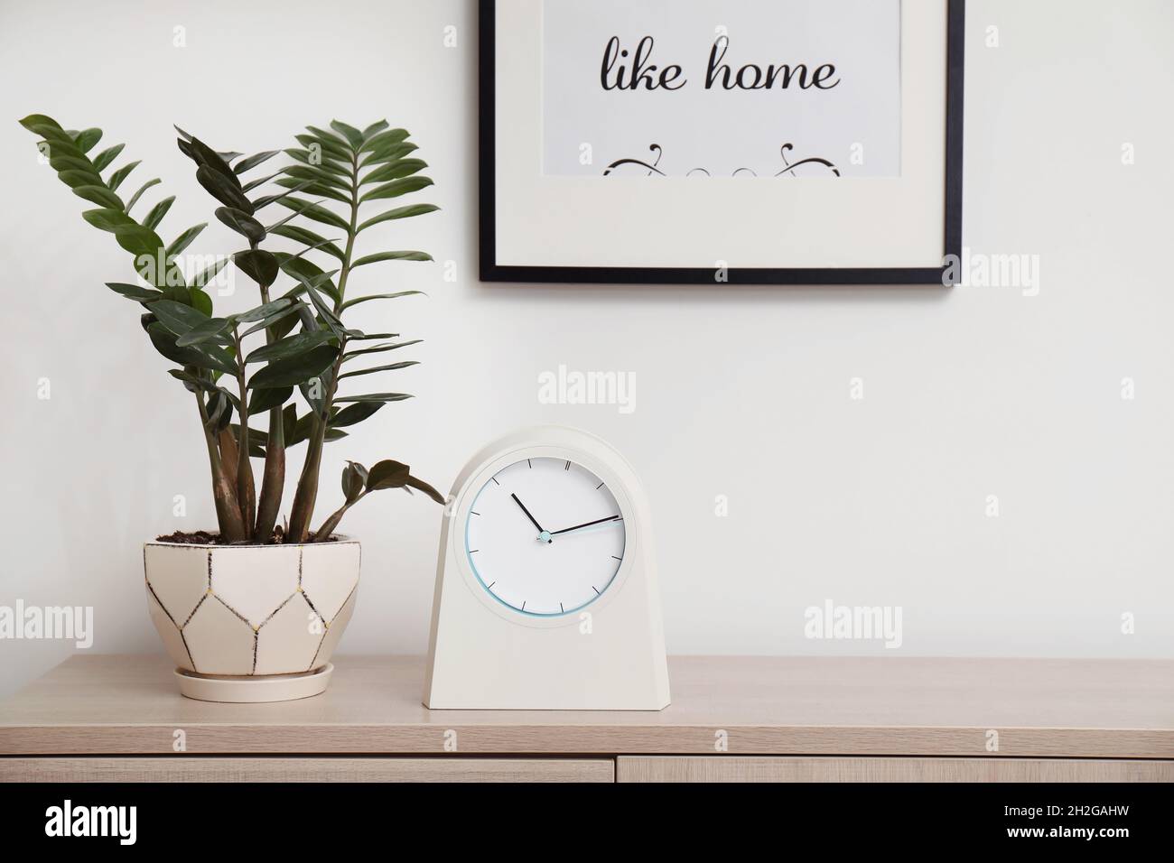 Modern clock on chest of drawers against light background Stock Photo ...