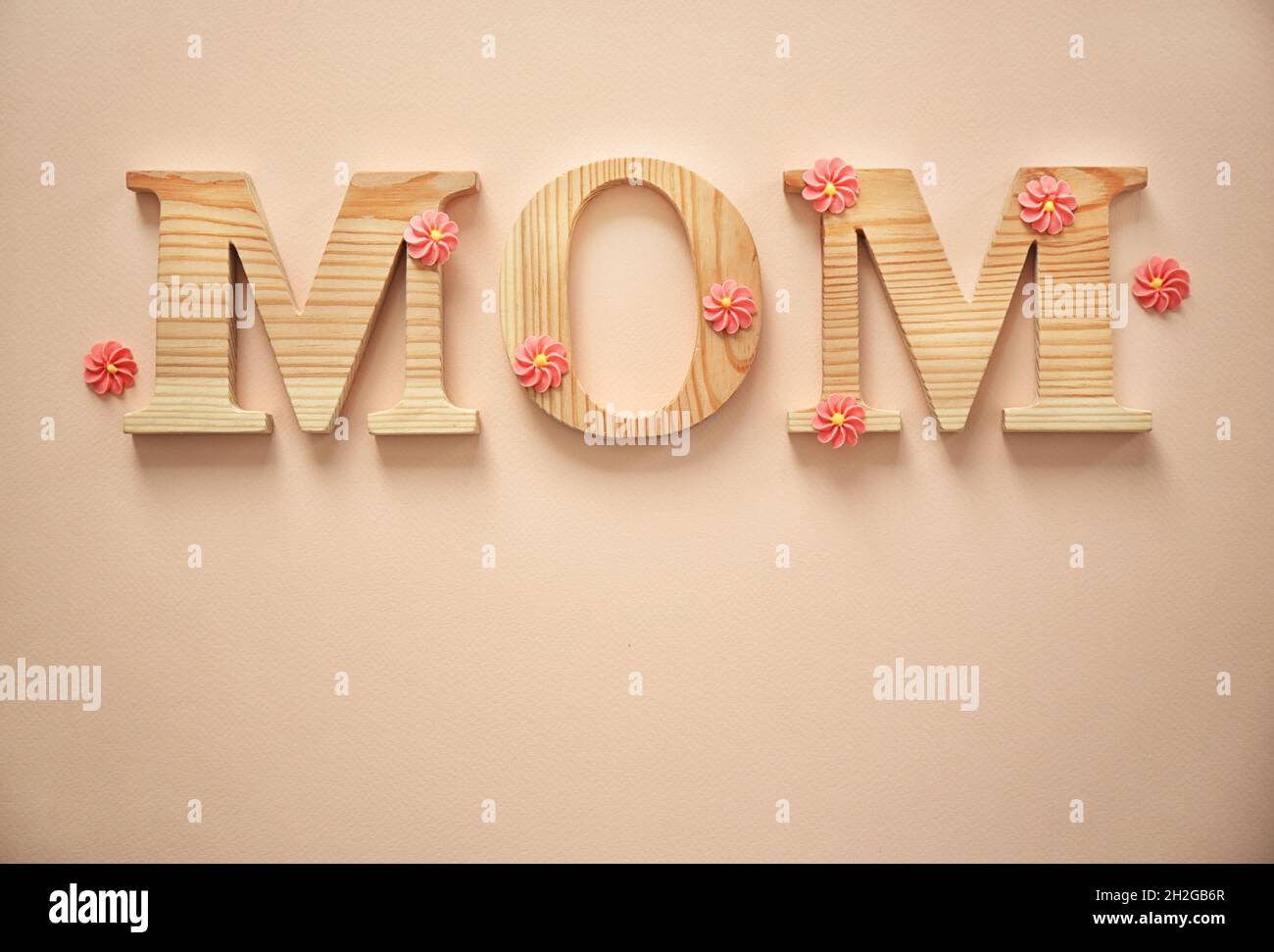 Word MOM made of wooden letters and flowers on light background, top ...
