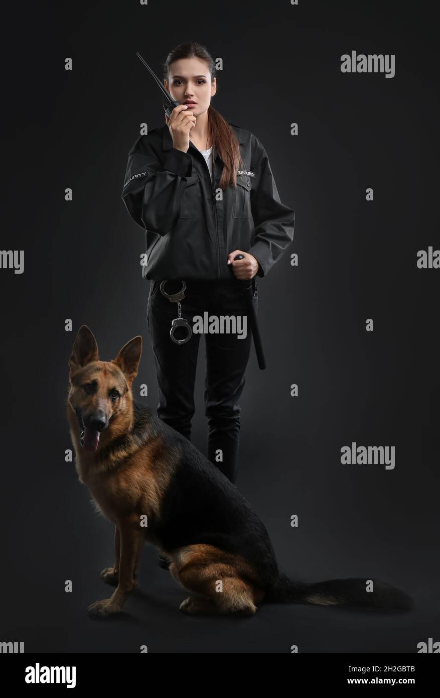 Female security guard with dog on dark background Stock Photo - Alamy
