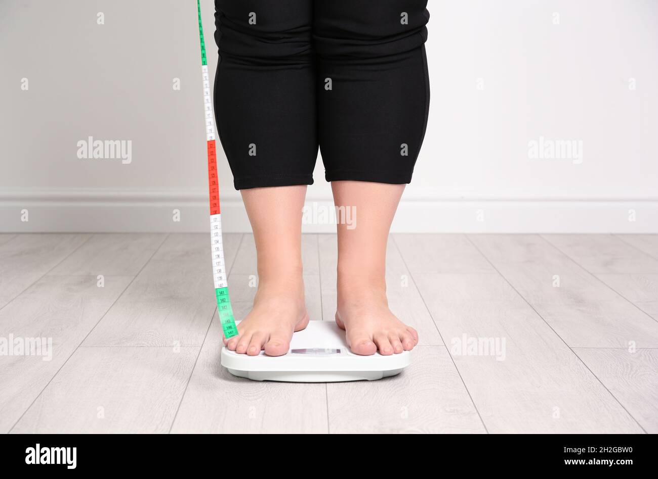 Overweight woman using scales indoors Stock Photo - Alamy
