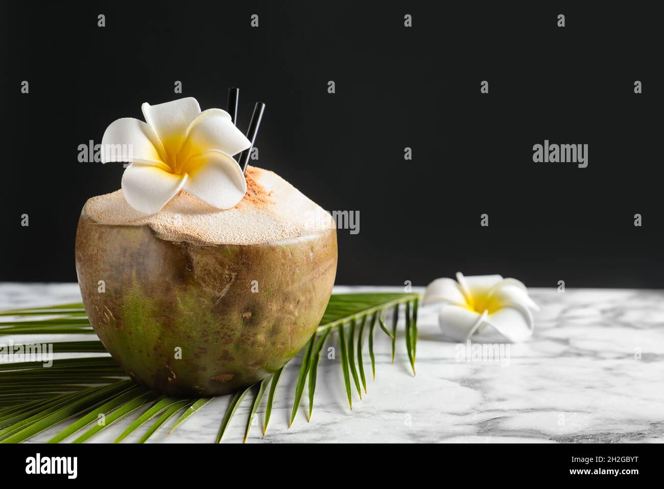 Fresh green coconut on table against dark background Stock Photo - Alamy